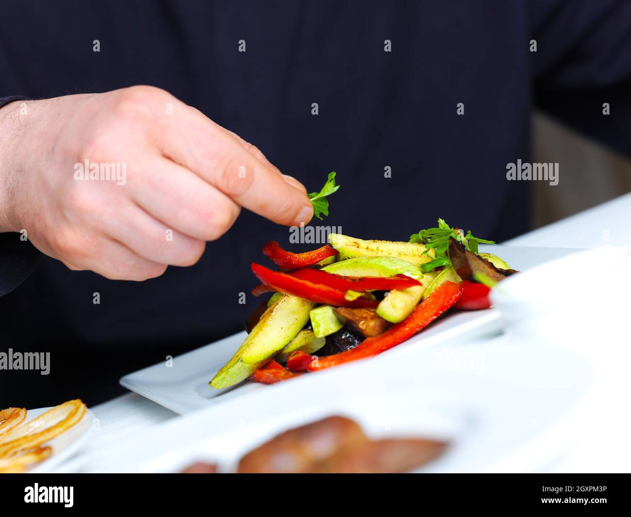 Handsome chef dressed in black uniform decorating tasty food in ...