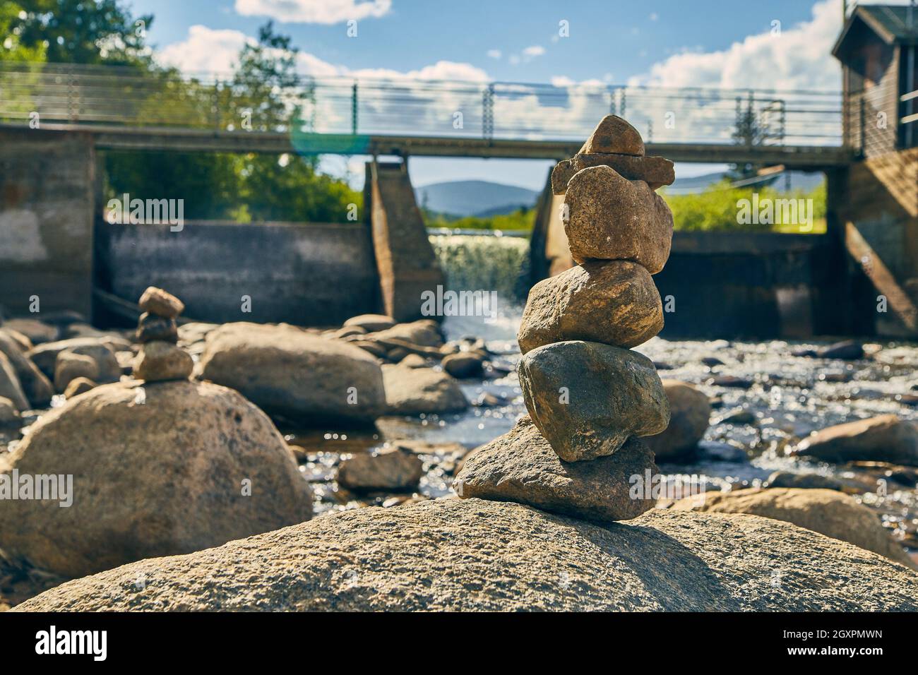 Stack of stones cairn next to dam river with walkway Stock Photo - Alamy