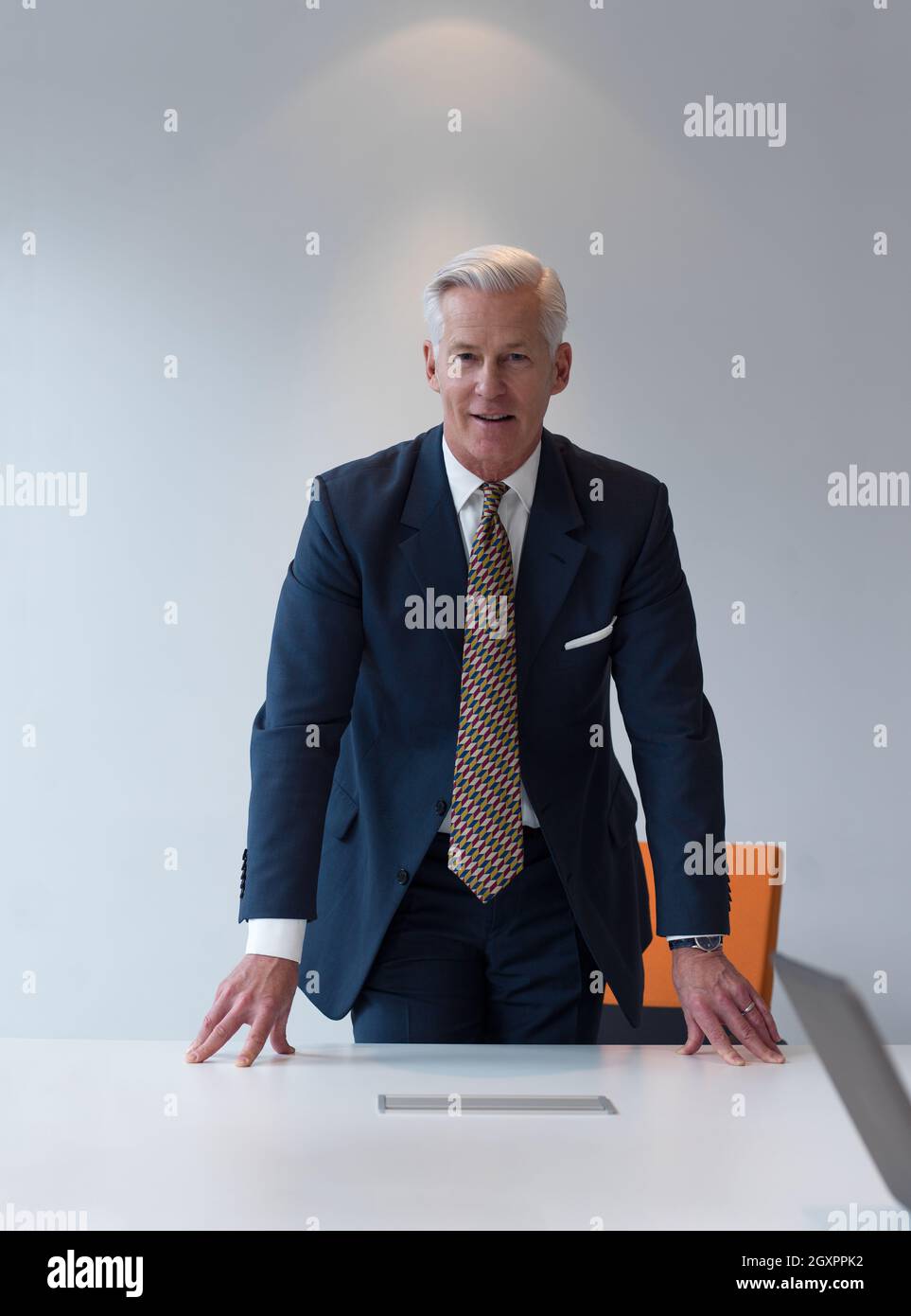 confident and handsome senior business man standing behind table in ...