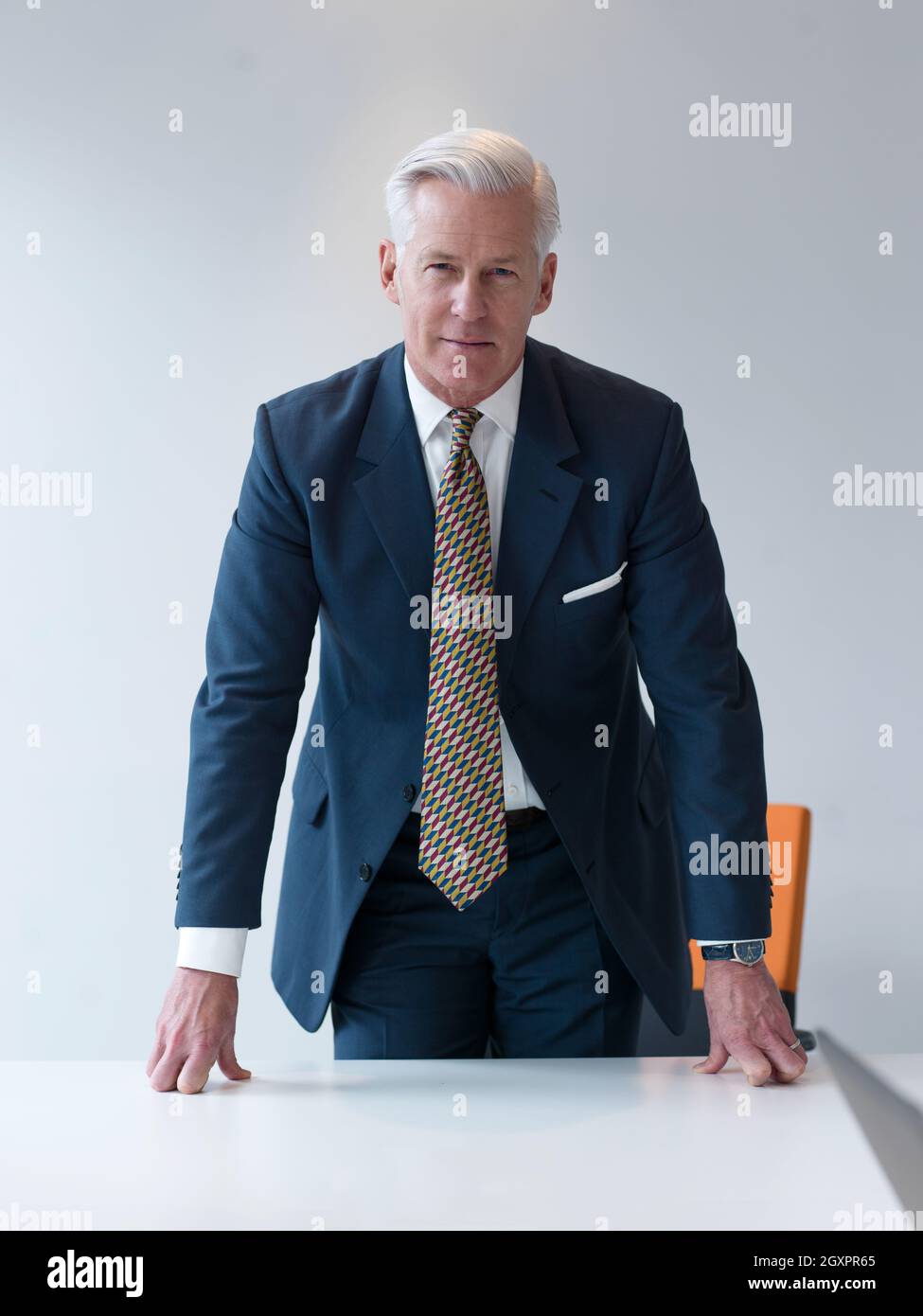 confident and handsome senior business man standing behind table in ...