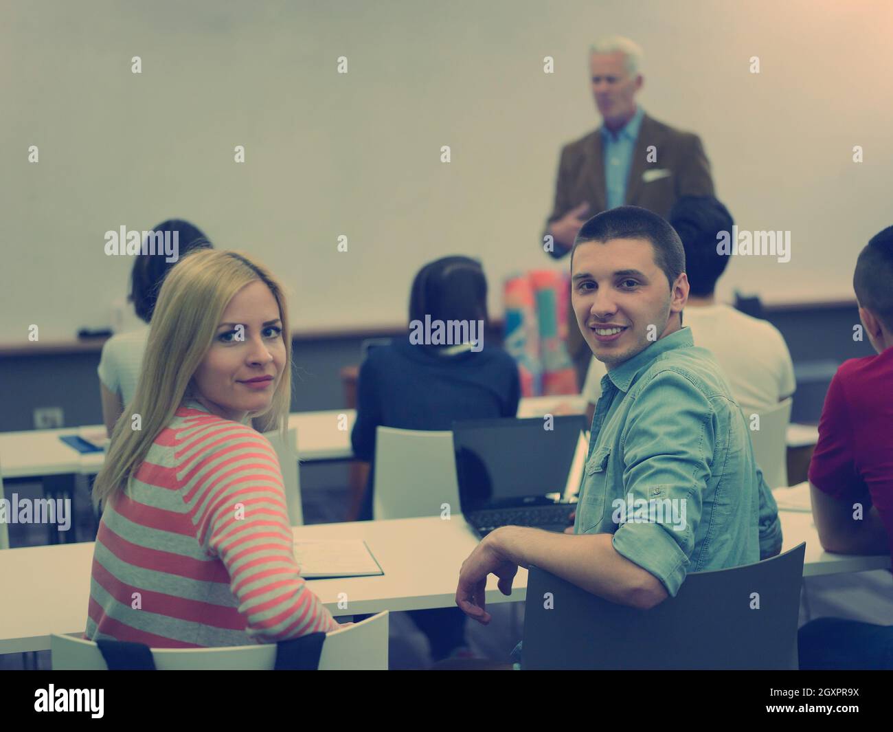 senior teacher with group of happy students in modern school classroom ...