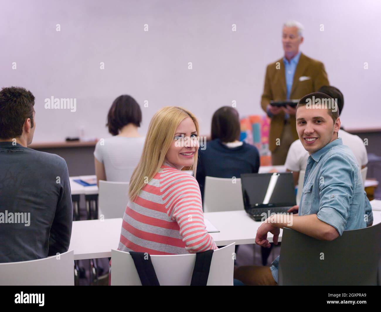 senior teacher with group of happy students in modern school classroom ...