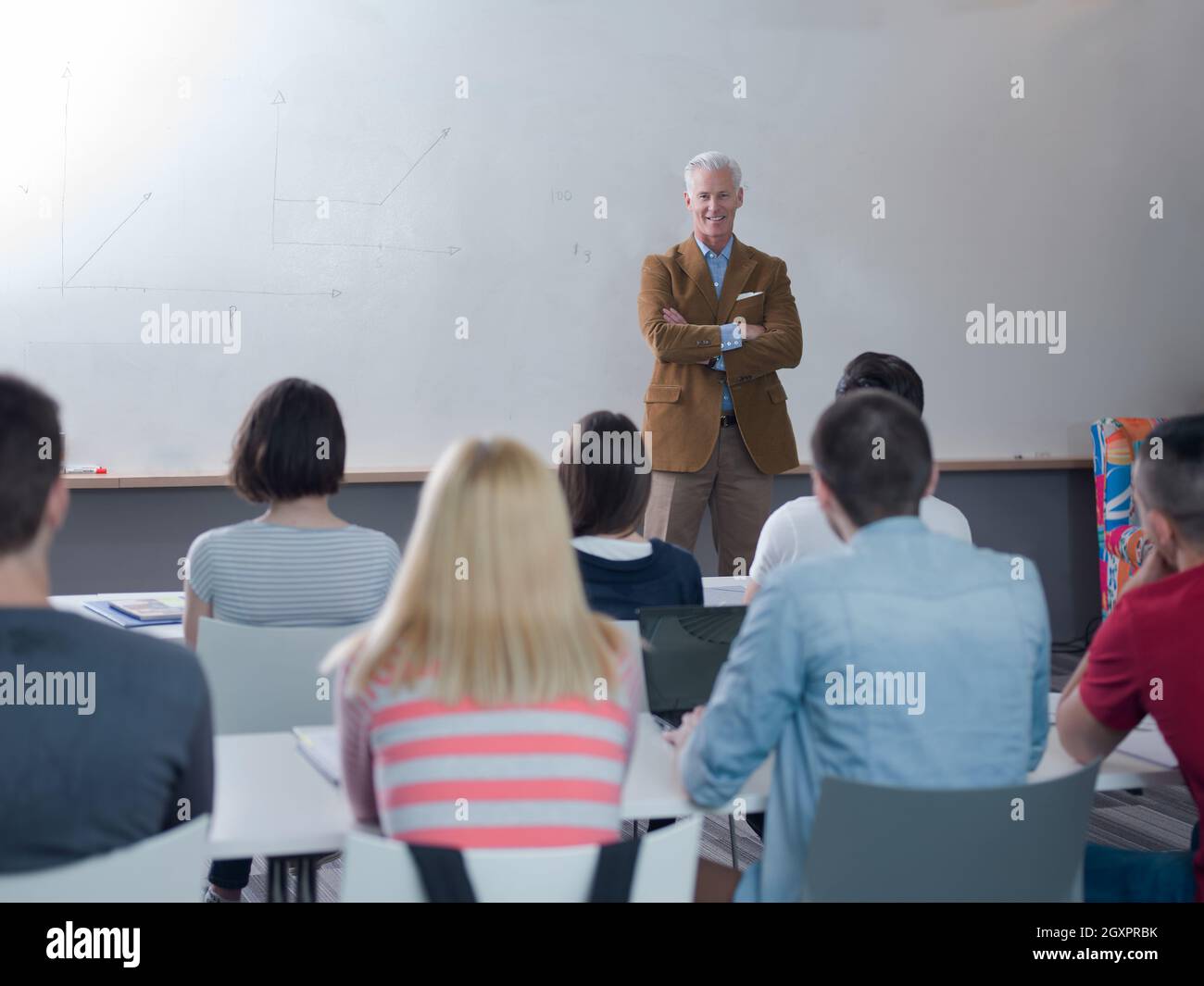 senior teacher with group of happy students in modern school classroom ...