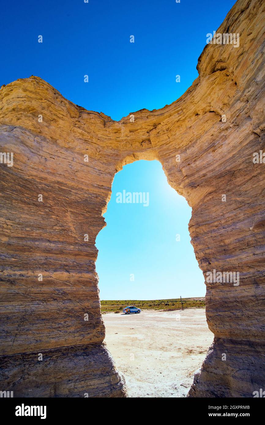 Arch through pillar of white rock blocking sun and blue sky Stock Photo ...