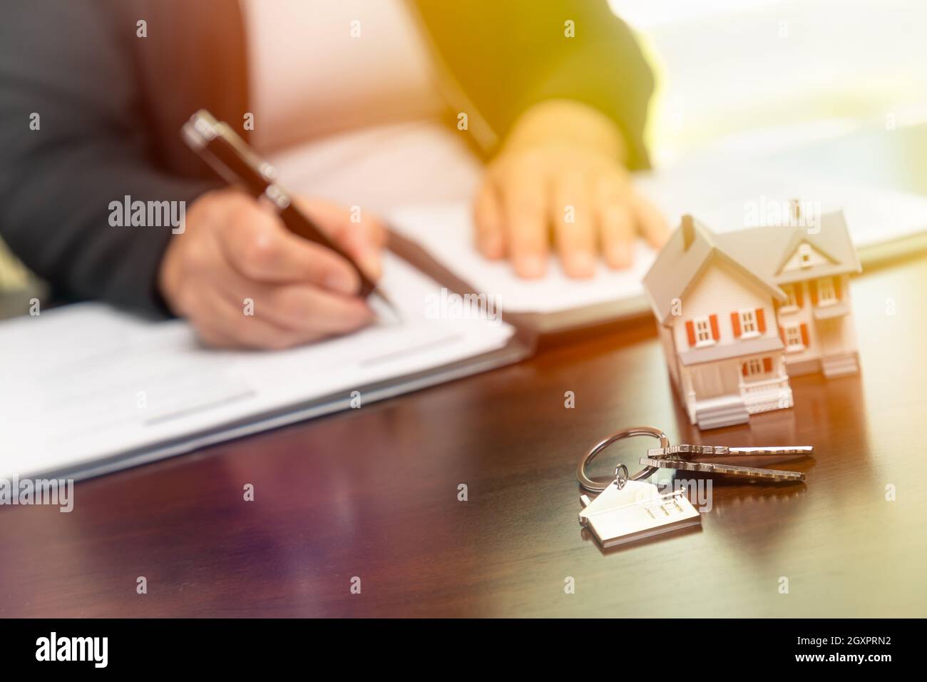 Woman signing real estate contract papers with house keys, home ...