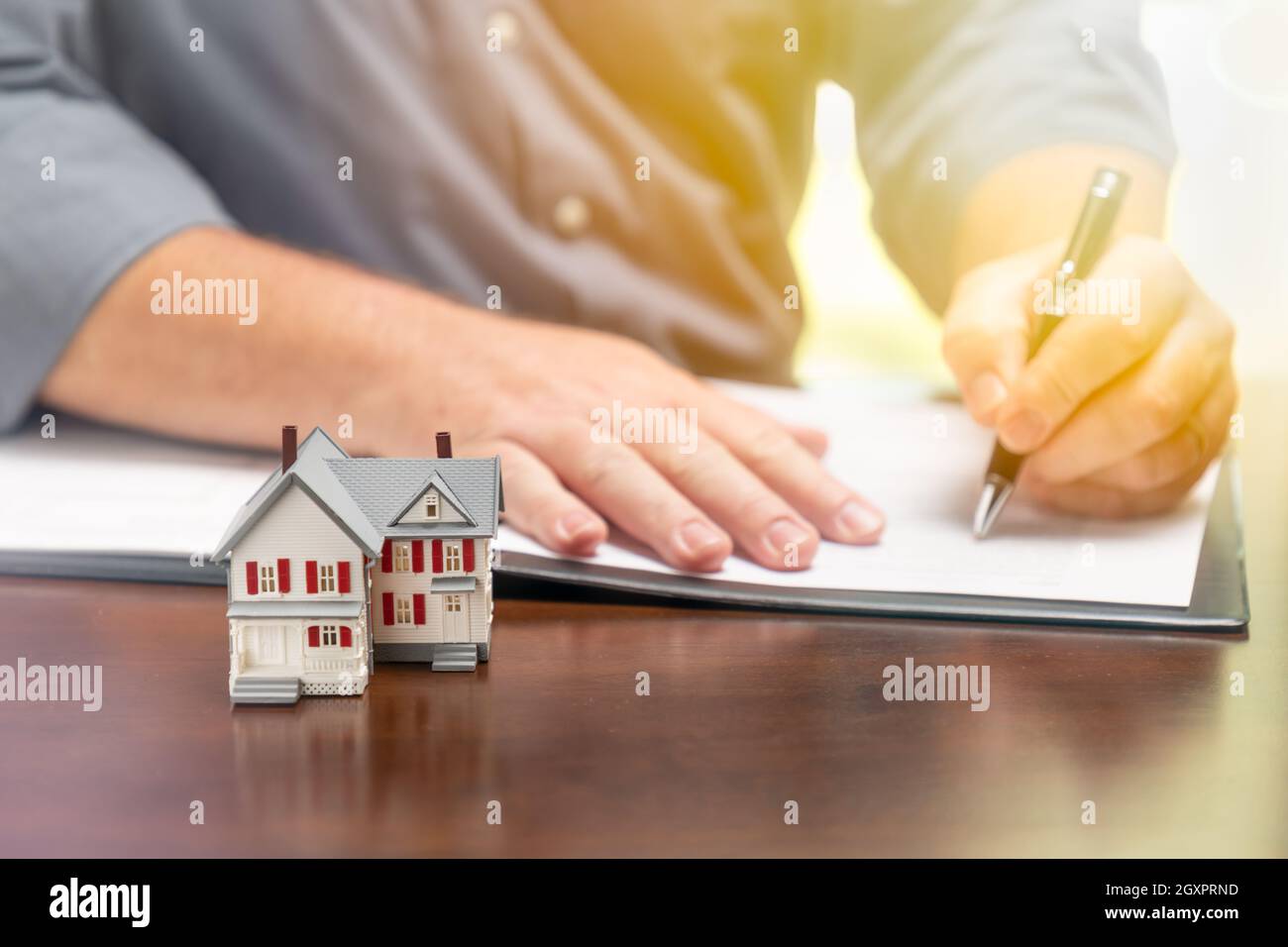 Man signing real estate contract papers with small model home in front ...