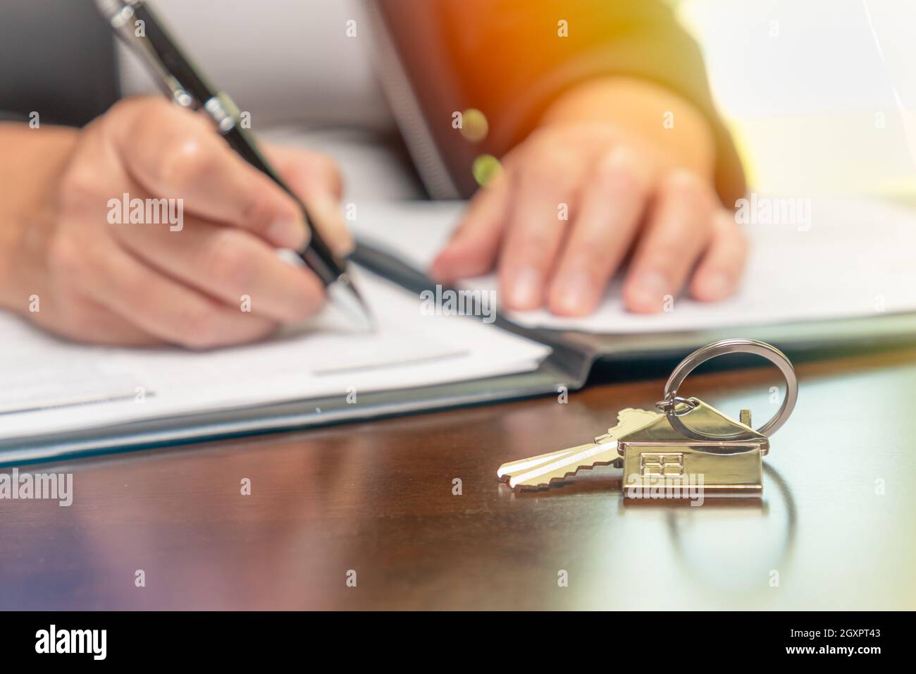 Woman signing real estate contract papers with house keys and home ...