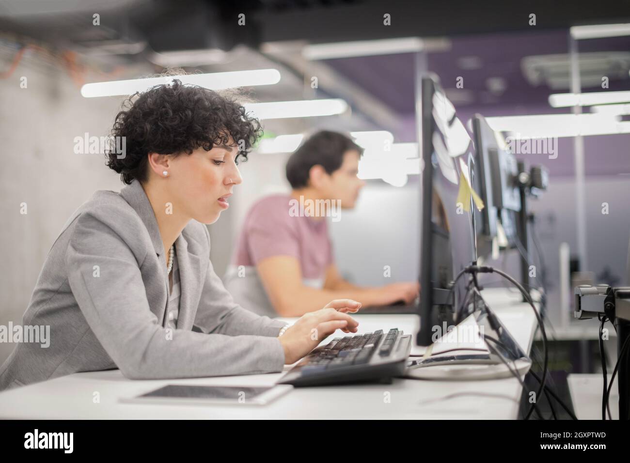 young female software developer using desktop computer while writing programming code at modern ...