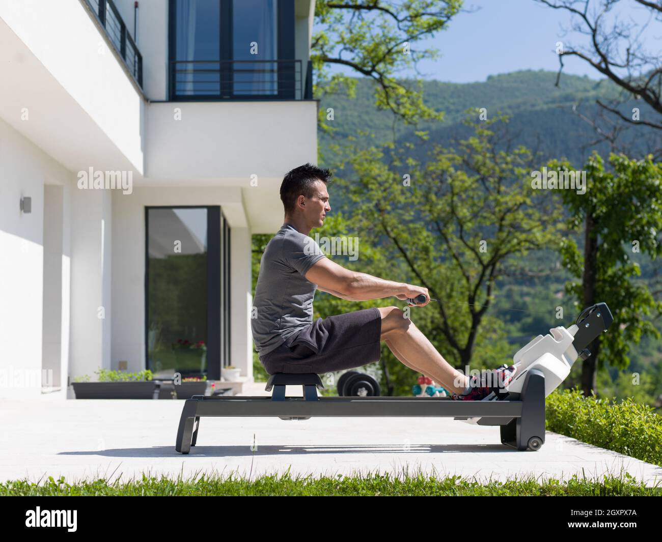 young handsome man doing morning exercises in front of his luxury home ...