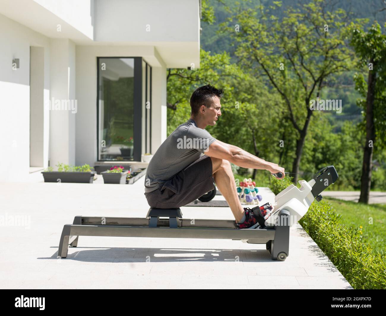 young handsome man doing morning exercises in front of his luxury home ...