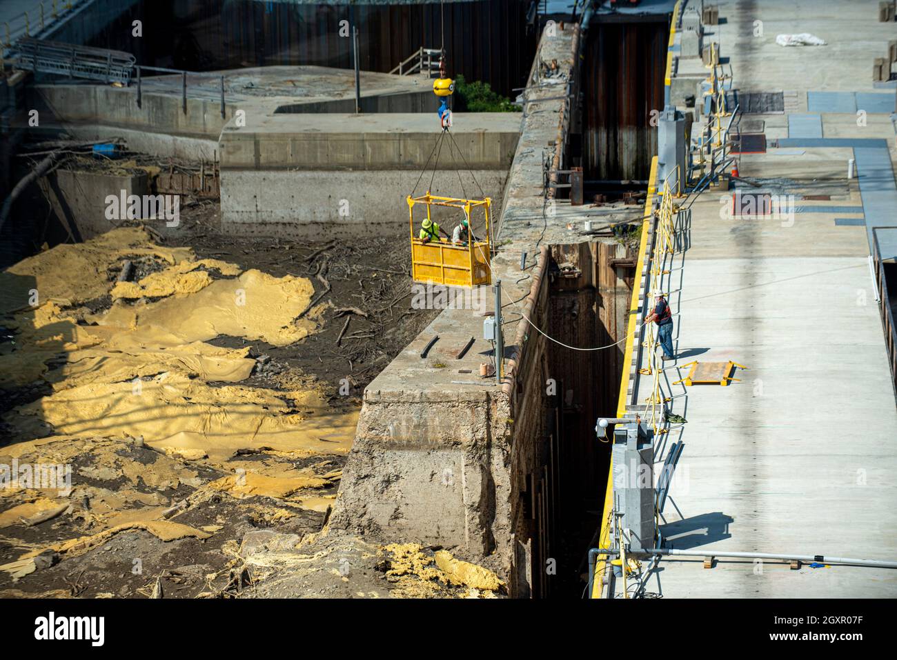 Contractors use a man basket to remove items from the old lock wall ...