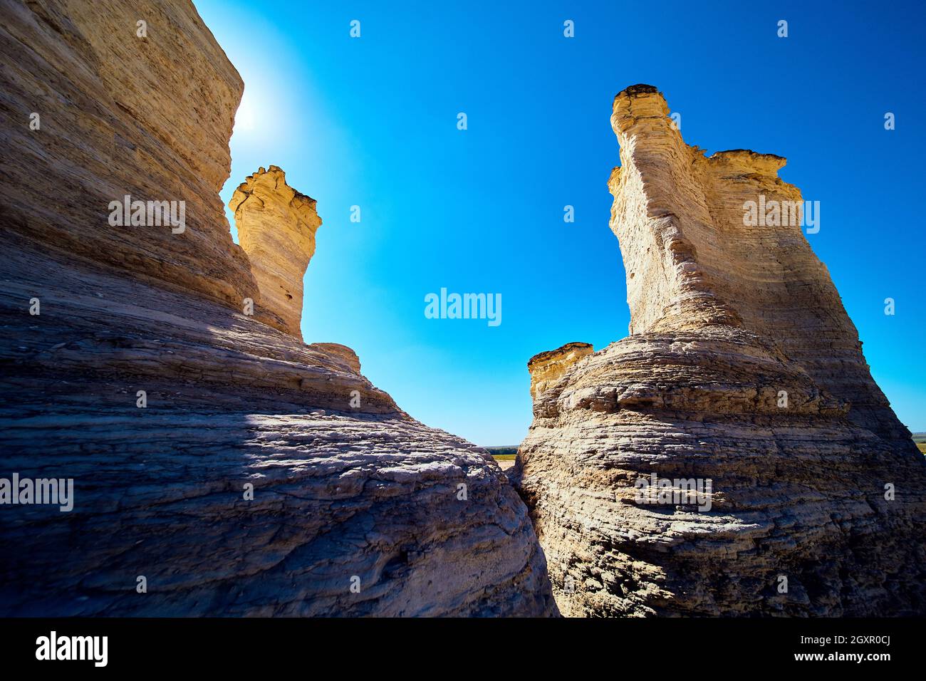 Pillars of white and gold rock blocking sun in desert against blue sky ...