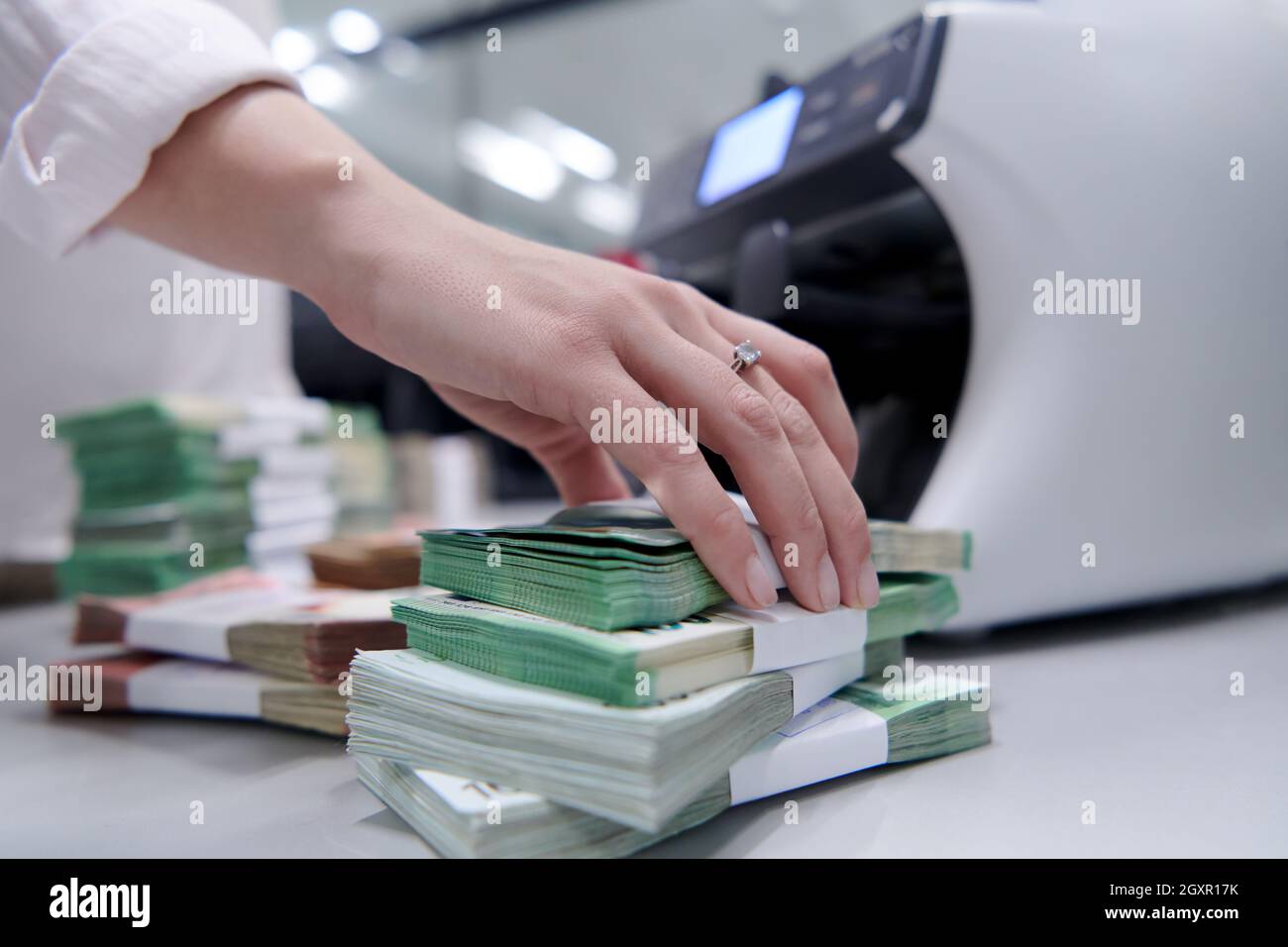 Bank employees using money counting machine while sorting and counting ...