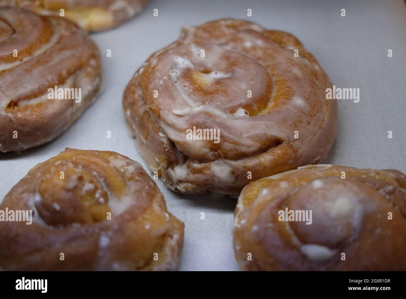 Closeup of several glazed cinnamon buns on display at local bakery ...