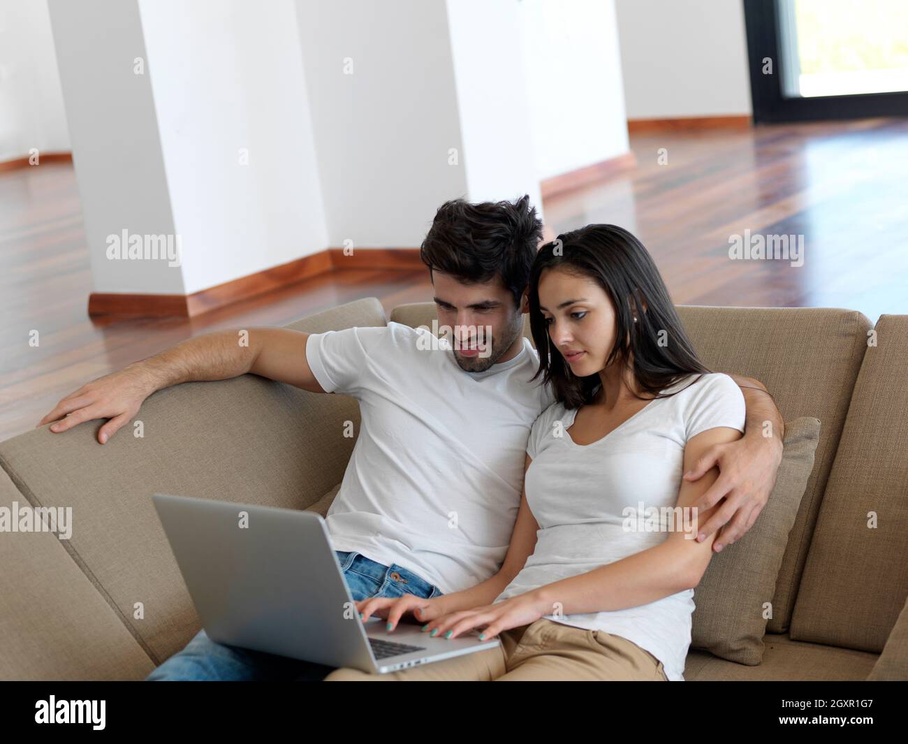 happy young relaxed couple working on laptop computer at modern home ...