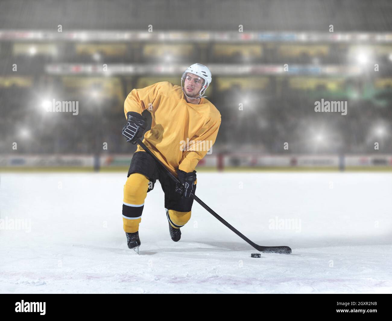 ice hockey player in action kicking with stick in front of big modern ...