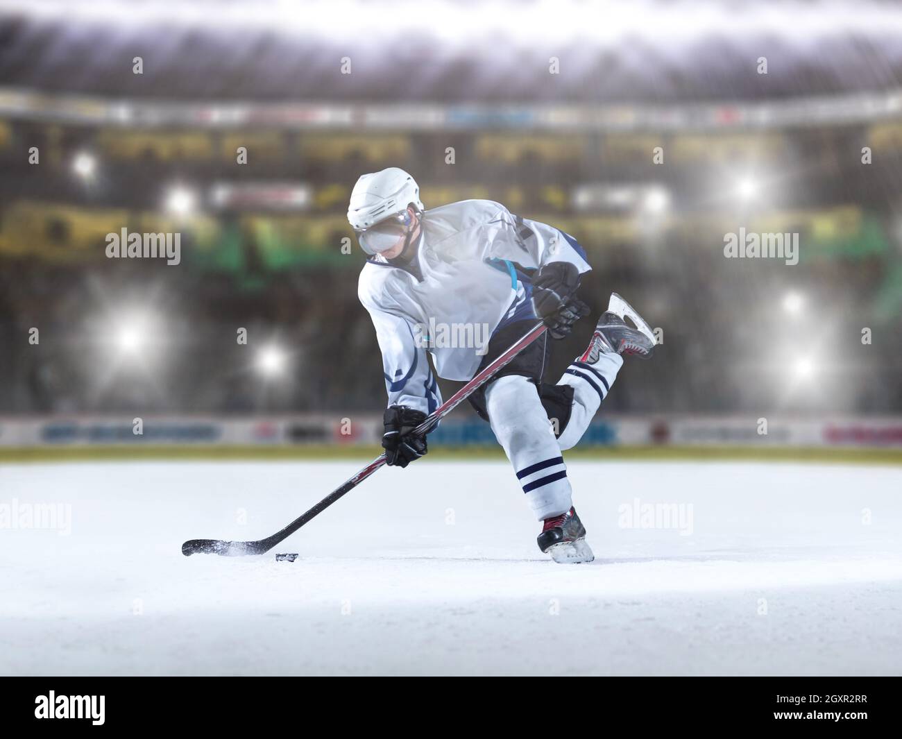 ice hockey player in action kicking with stick in front of big modern ...