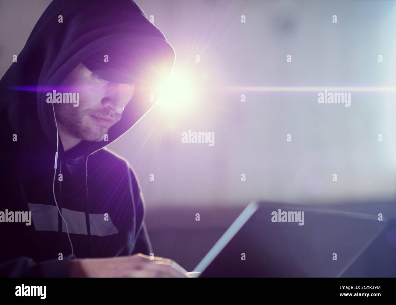 Young talented hacker using laptop computer while working in dark ...