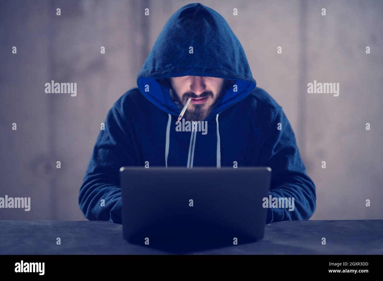 Young talented hacker smoking cigarette while working on laptop ...