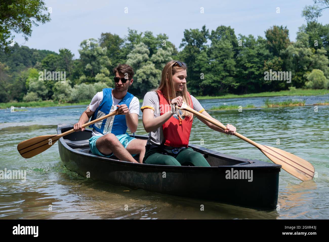 Couple adventurous explorer friends are canoeing in a wild river ...