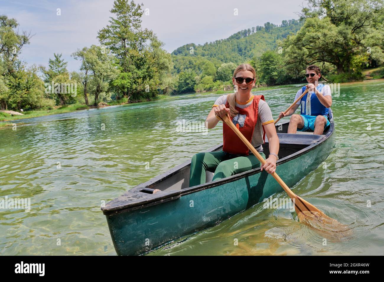 Couple adventurous explorer friends are canoeing in a wild river ...
