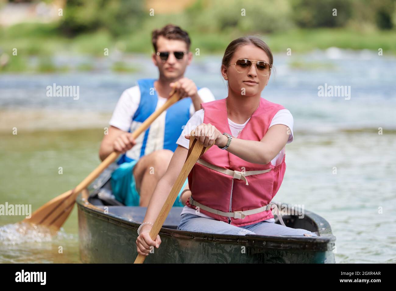 Couple adventurous explorer friends are canoeing in a wild river ...