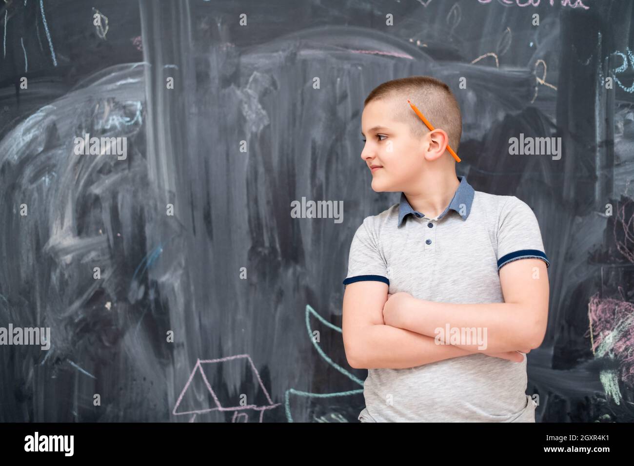 portrait of happy boy with orange wooden pen behind the ear standing in ...