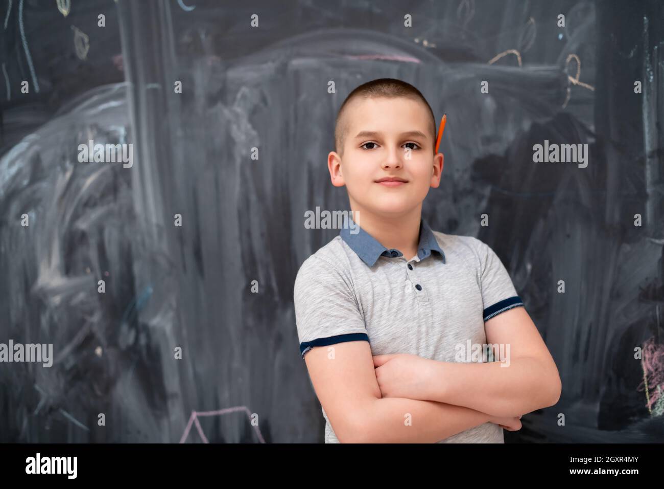 portrait of happy boy with orange wooden pen behind the ear standing in ...