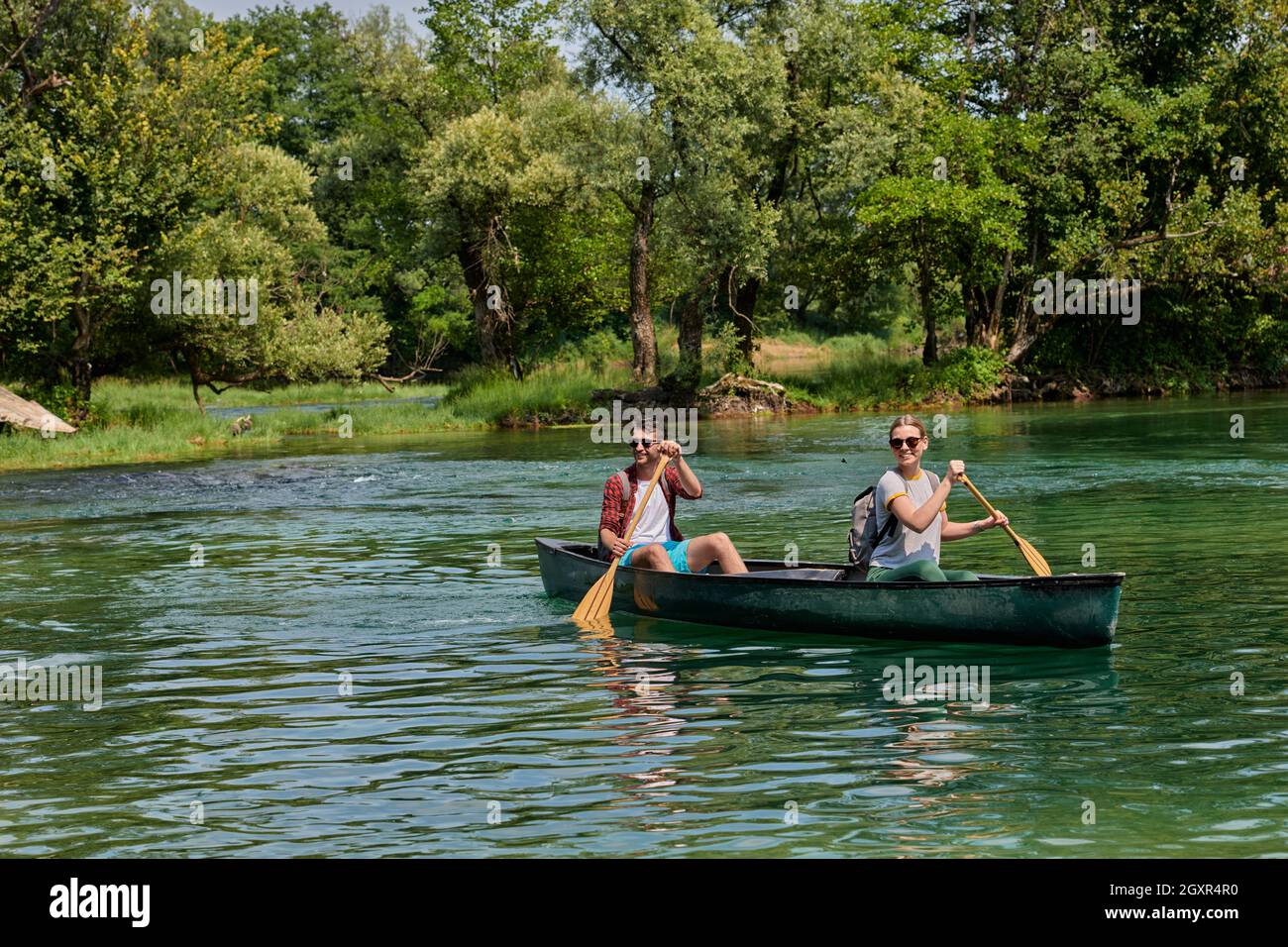Couple adventurous explorer friends are canoeing in a wild river ...