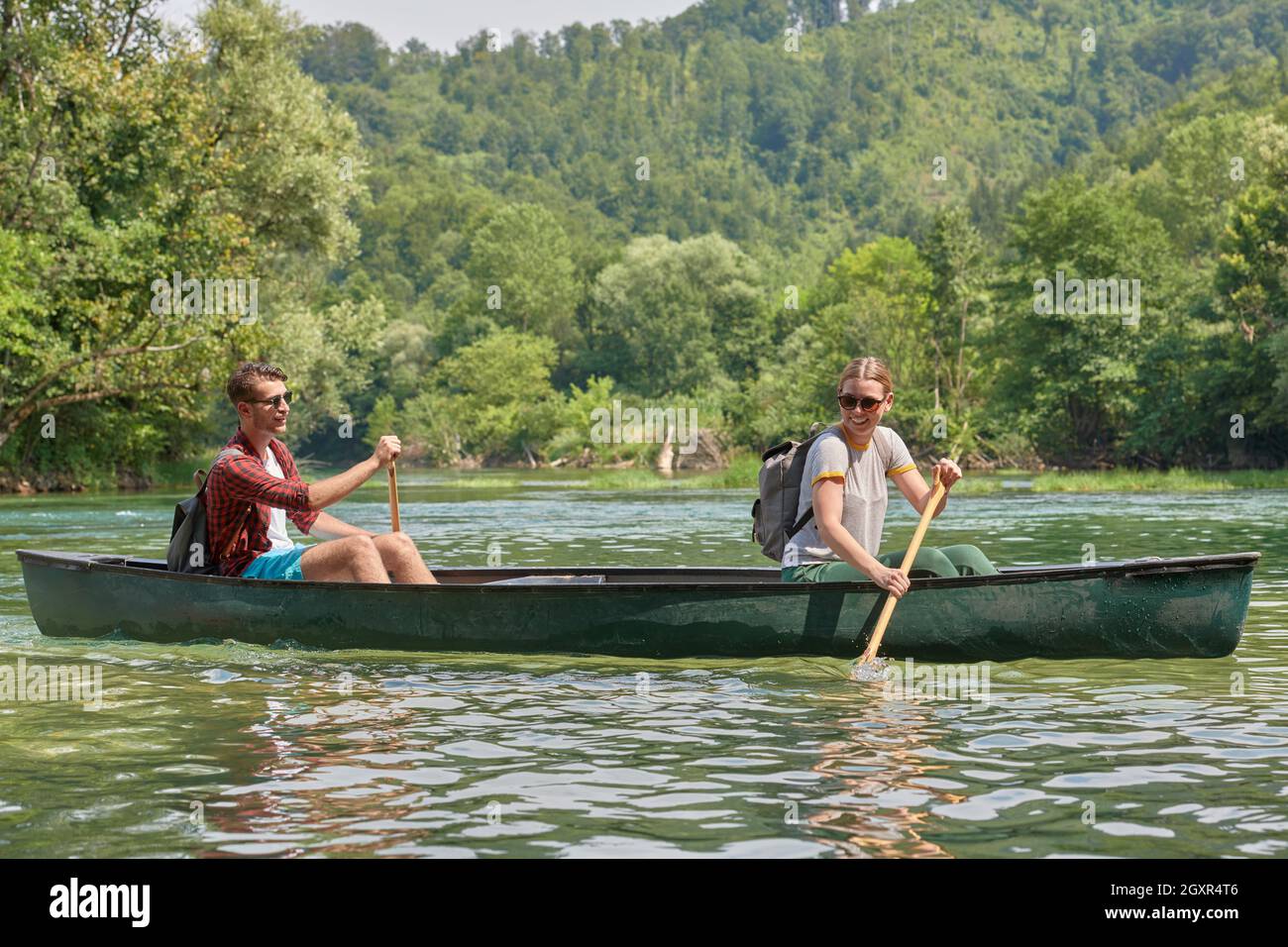 Couple adventurous explorer friends are canoeing in a wild river ...
