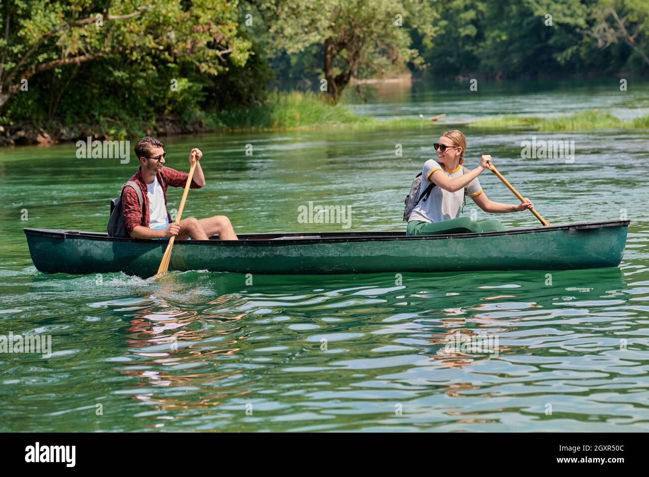 Couple adventurous explorer friends are canoeing in a wild river ...