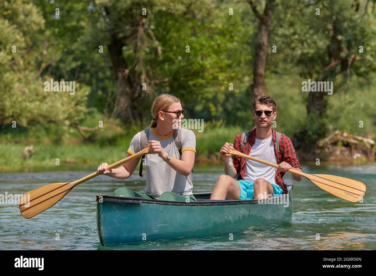 Couple adventurous explorer friends are canoeing in a wild river ...