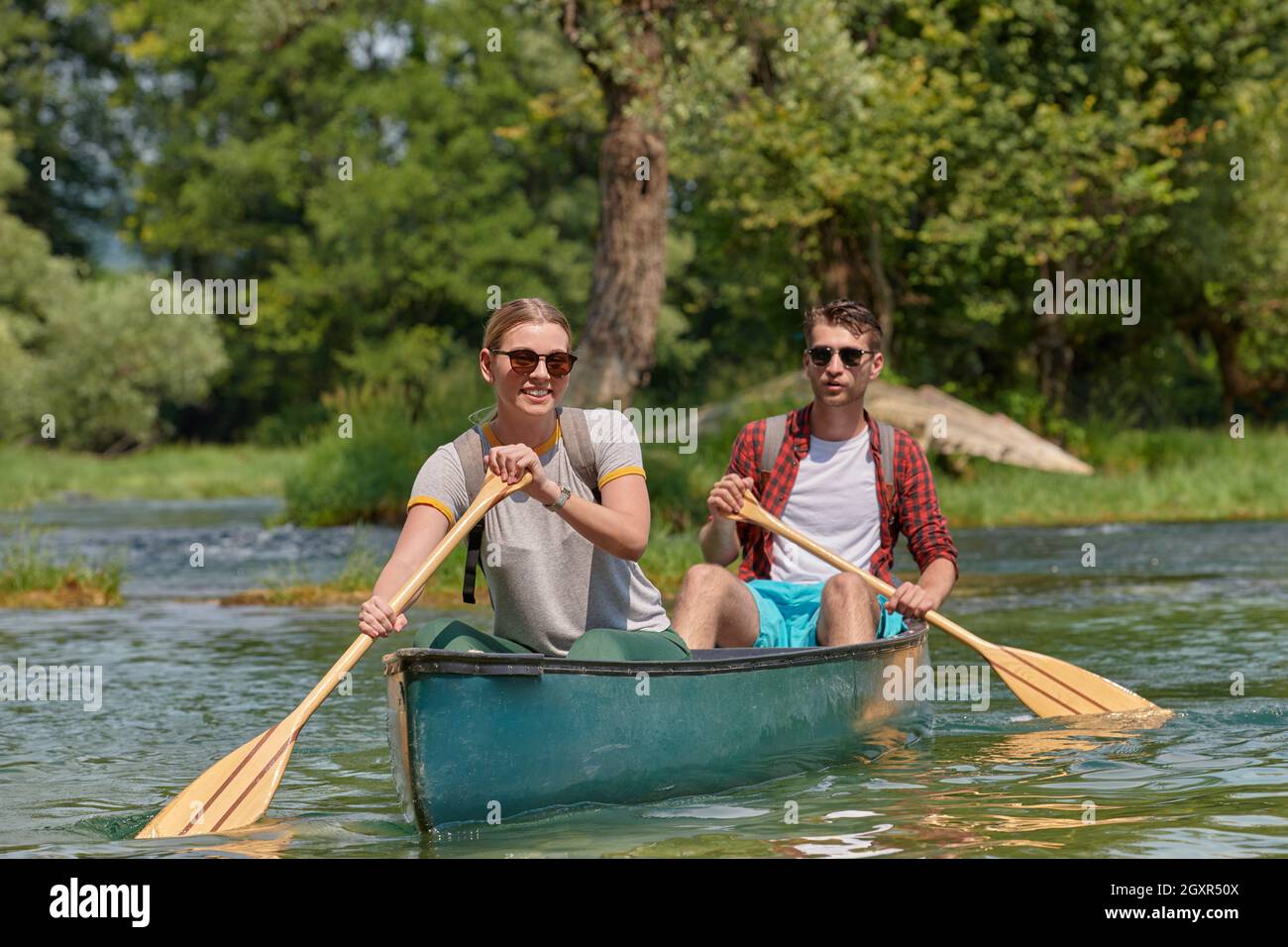 Couple adventurous explorer friends are canoeing in a wild river ...