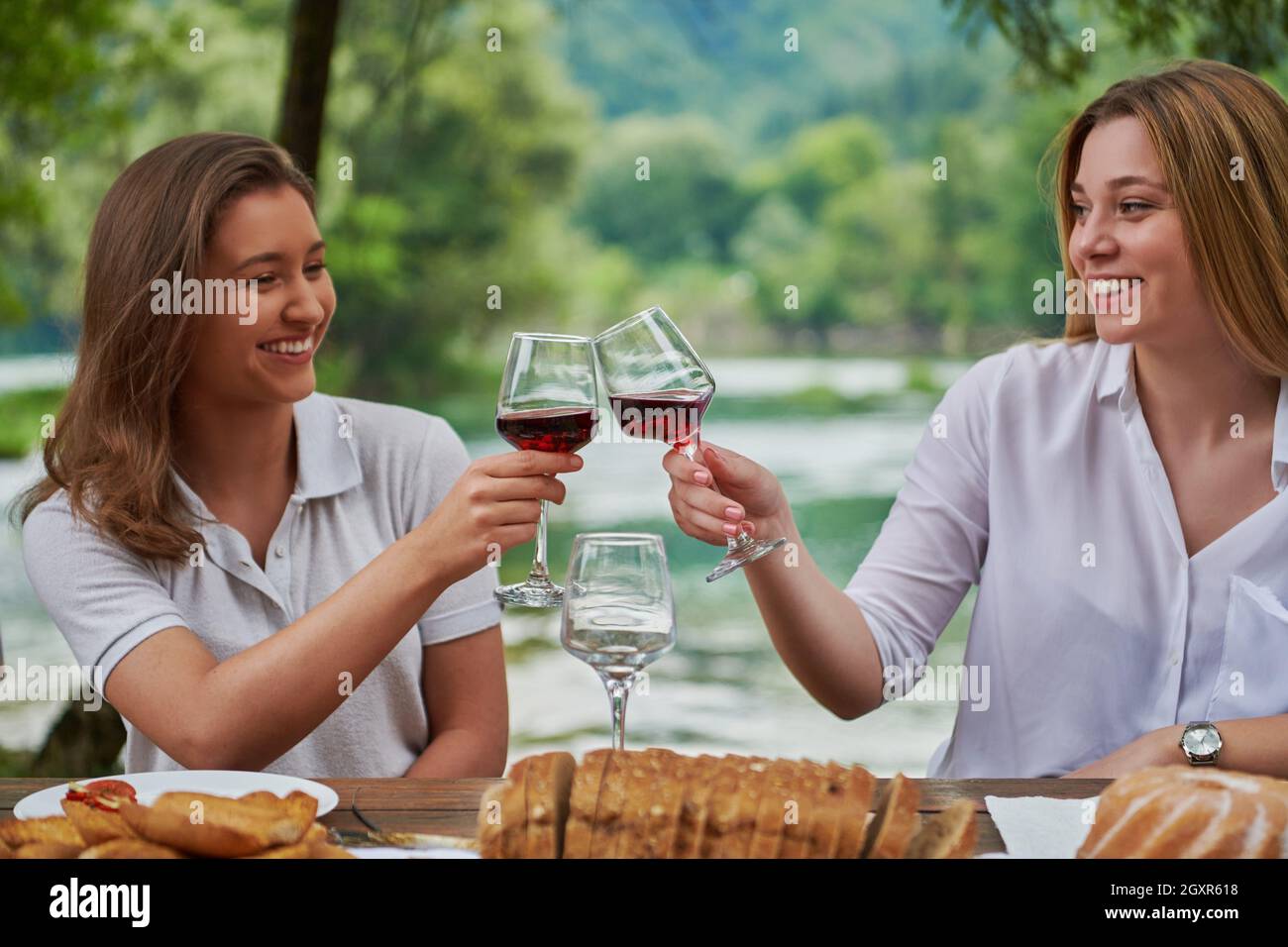 two young happy girlfriends having picnic french dinner party outdoor ...