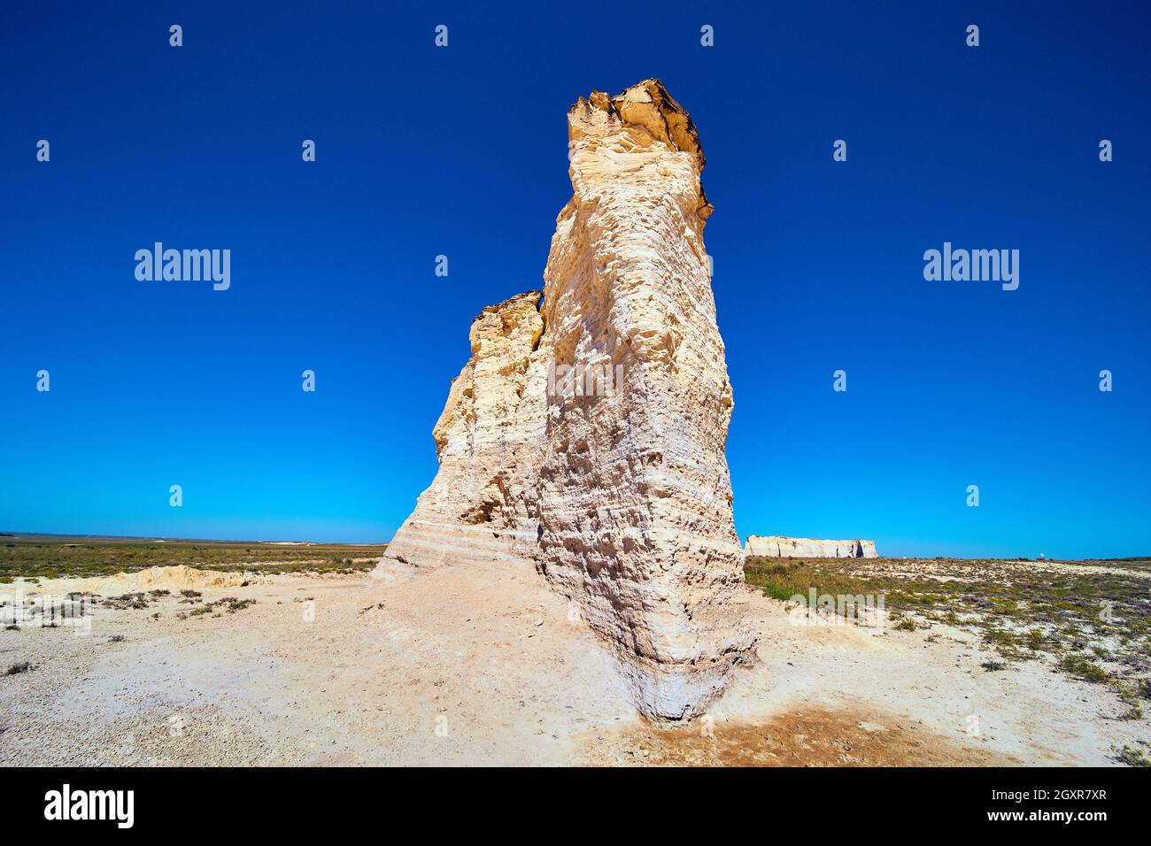 Giant pillar of white rock sticking out of flat desert landscape ...