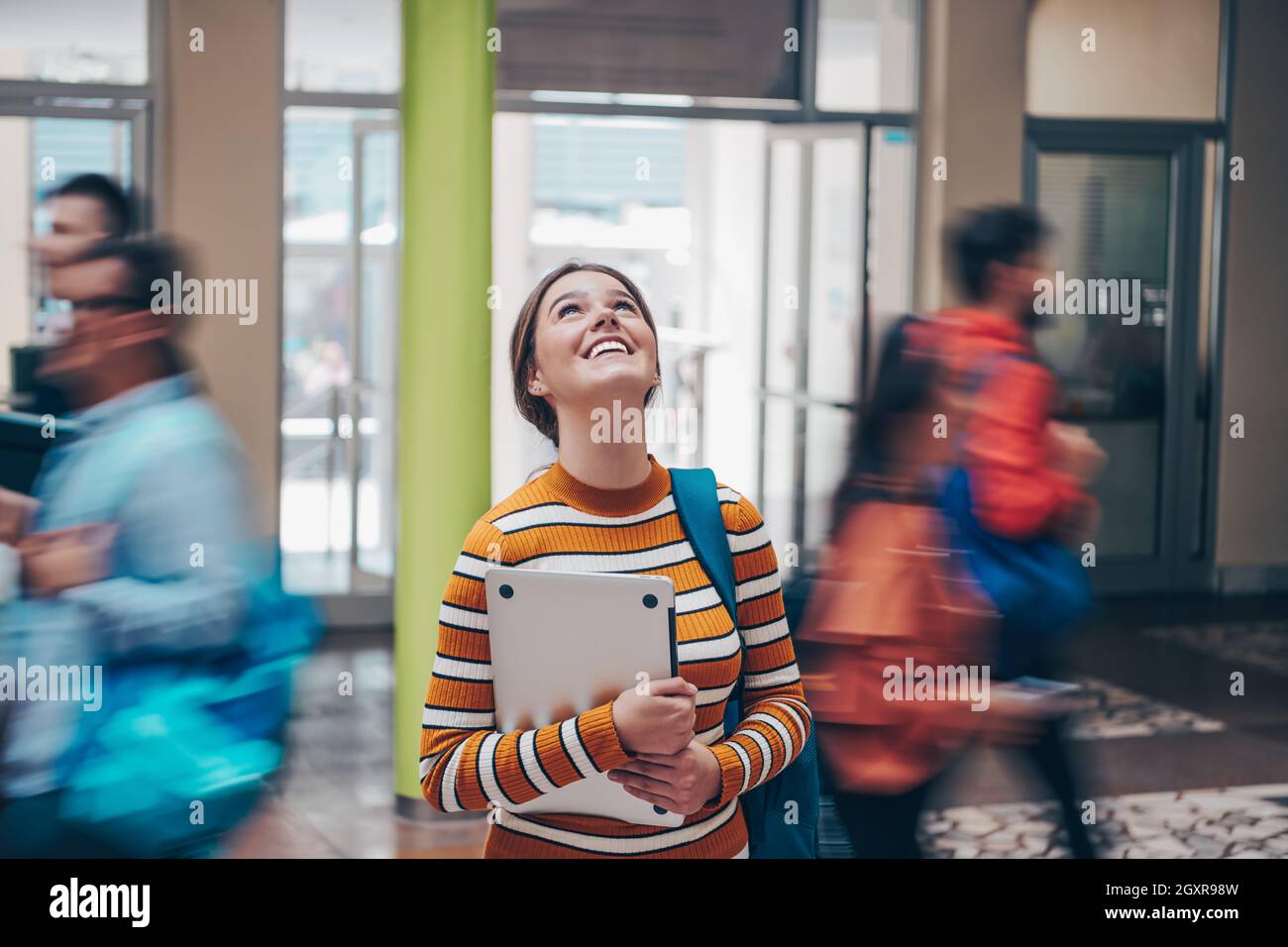 portrait of a happy young student getting ready for class while waiting ...