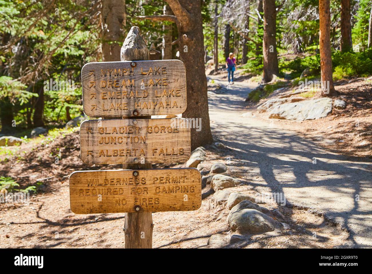 Hiking sign trailhead leading path to lake in mountain with hiker in ...