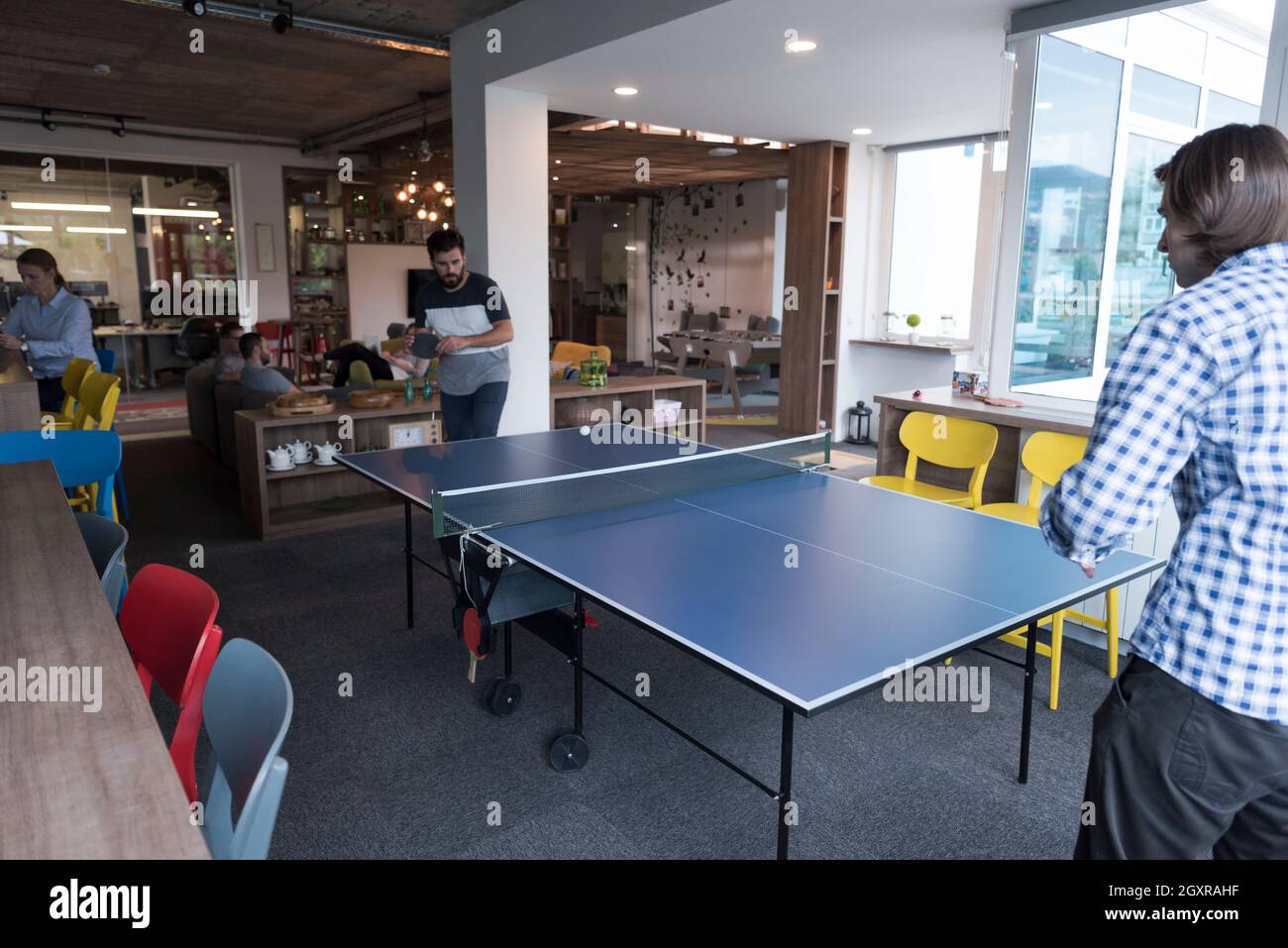 Two young start up business man playing ping pong tennis at modern ...