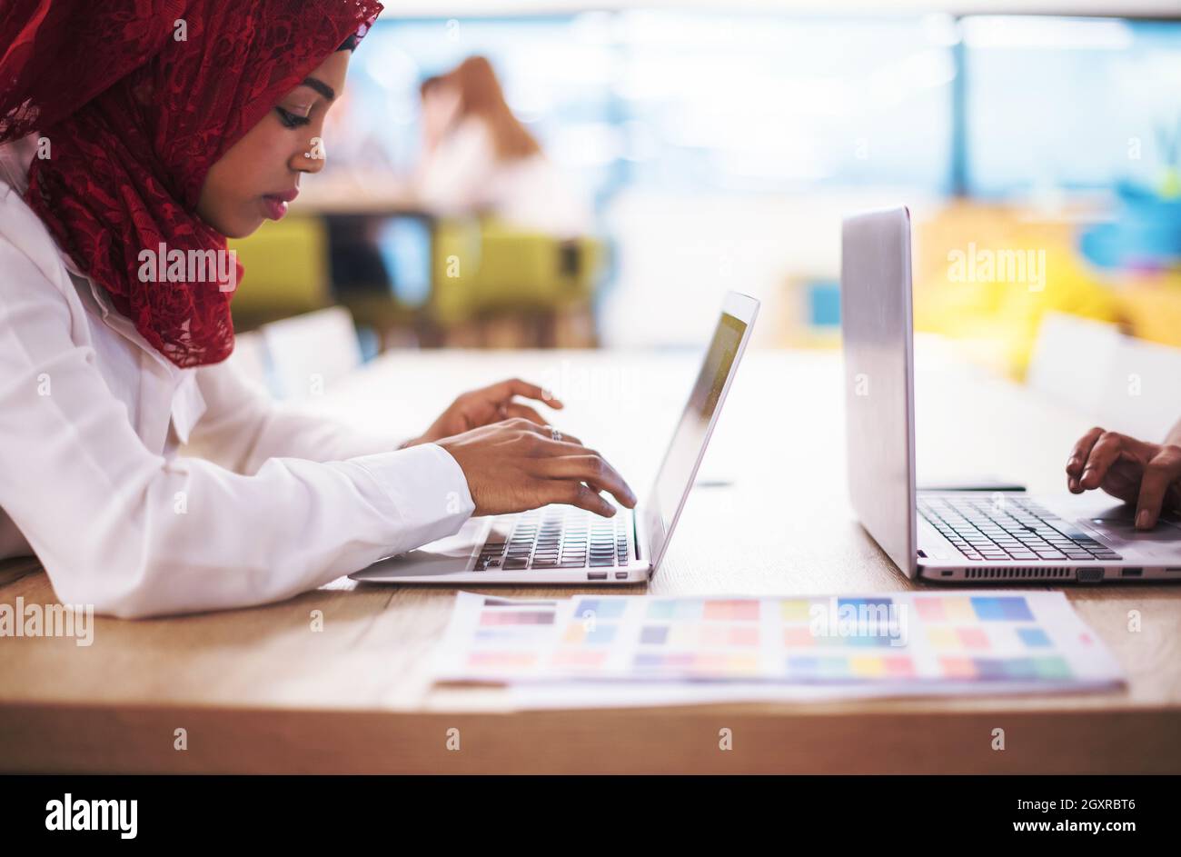 Young modern black muslim business woman wearing a red hijab,working on ...