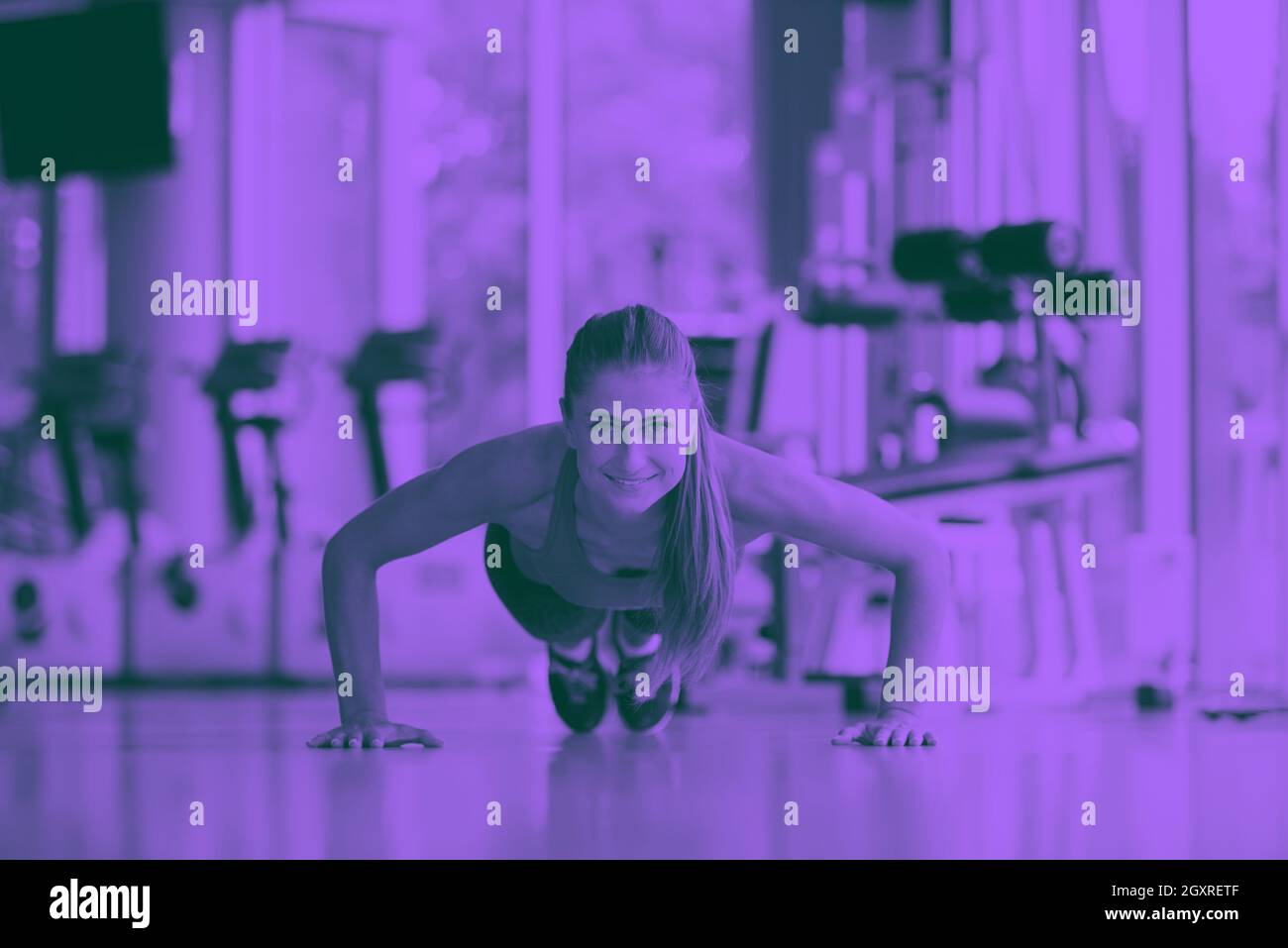 Gorgeous blonde woman warming up and doing some push ups a the gym duo ...