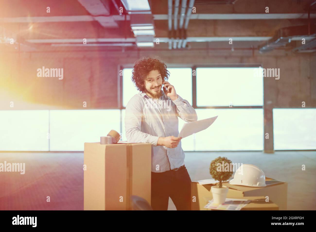 young male architect on construction site checking documents and ...