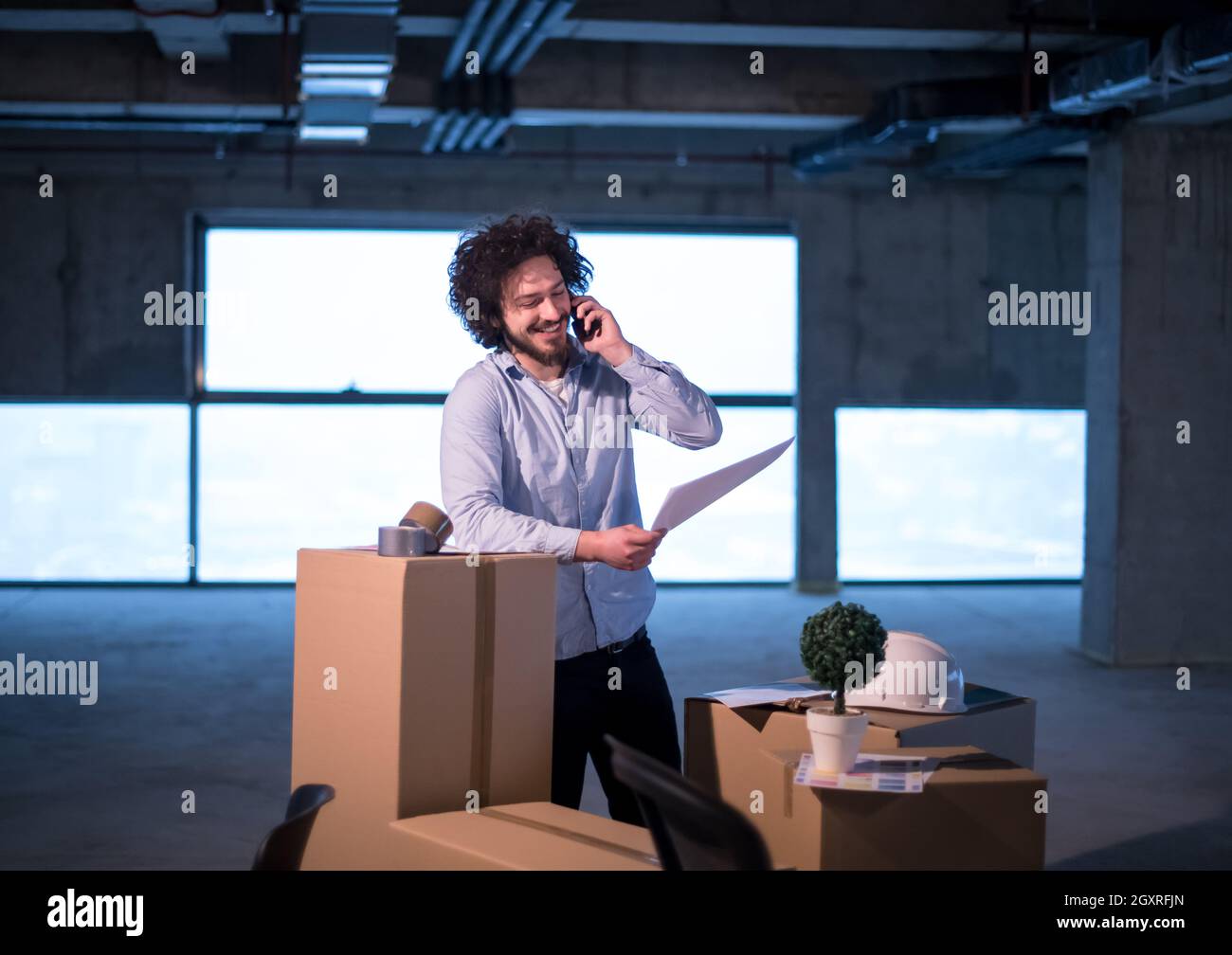 young male architect on construction site checking documents and ...