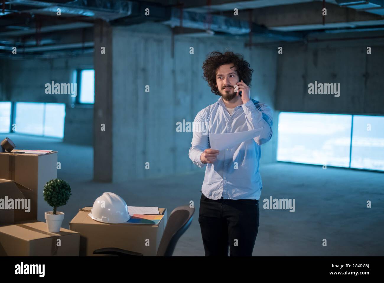 young male architect on construction site checking documents and ...
