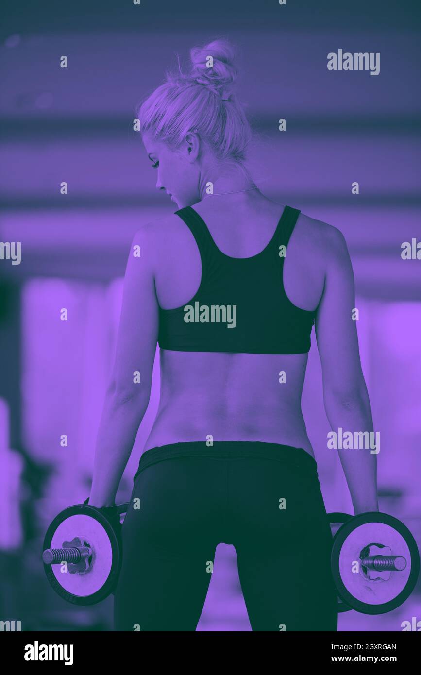 Gorgeou woman girl lifting some weights and working on her biceps in a ...
