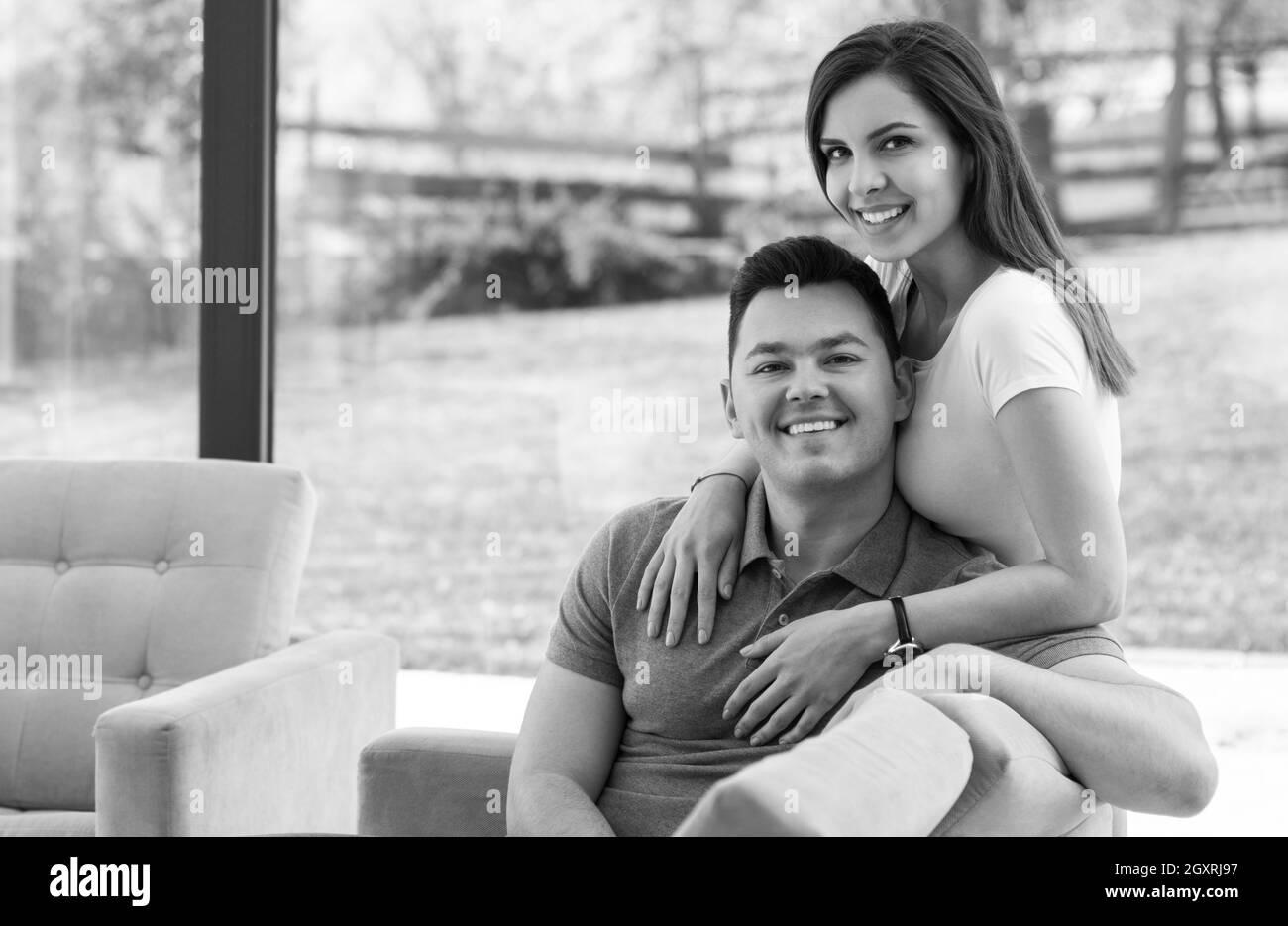 Two cheerful lovers sitting on the couch and huging Stock Photo - Alamy