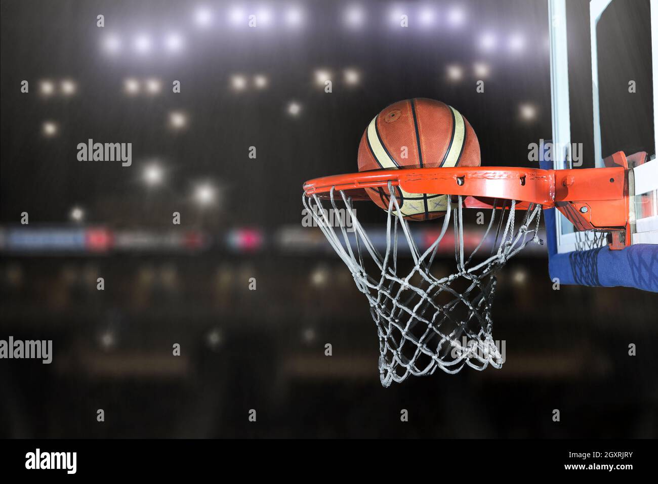 Basketball ball, board and net in front of big modern basketball arena ...