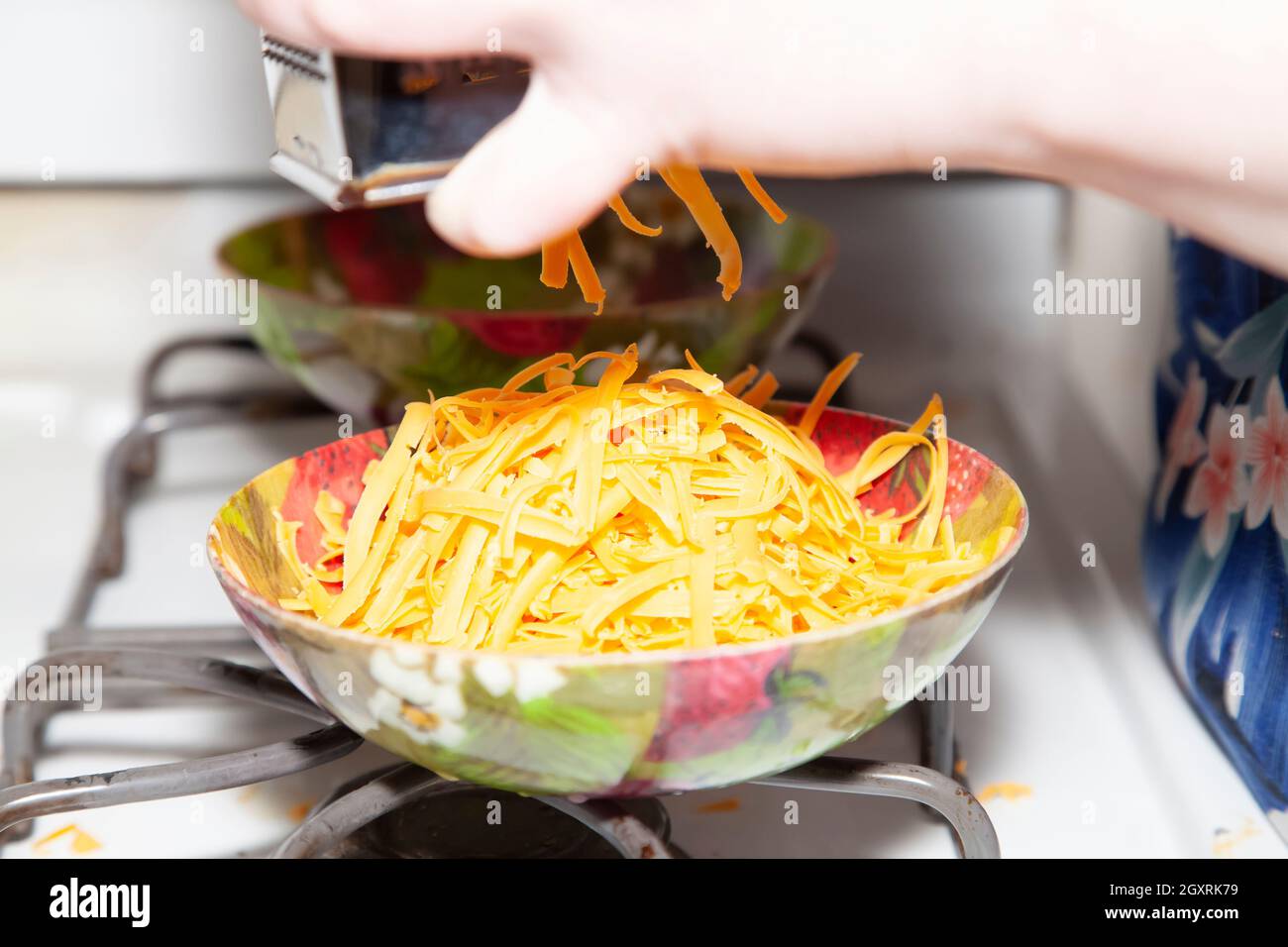 Woman's hands using a grater to shred cheese into a bright bowl Stock ...