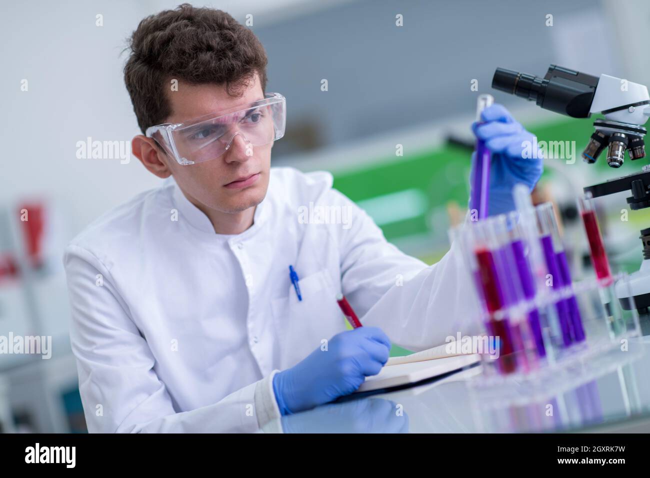 young student with protective glasses making chemistry experiment in ...