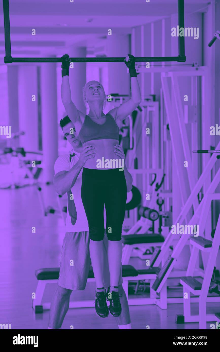 trainer support young woman while lifting on bar in fitness gym indoors ...