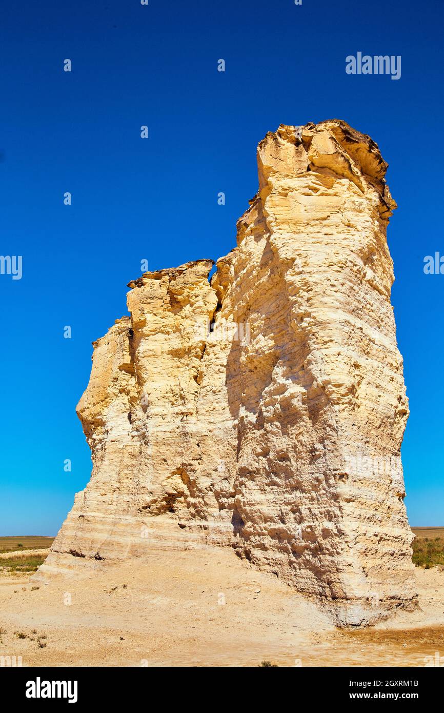 Close up of pillar of white rock sticking out of flat desert with blue ...
